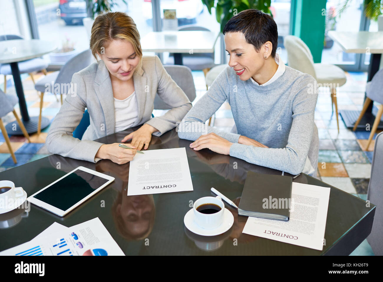 High angle portrait of two happy businesswomen signing contract sitting ...