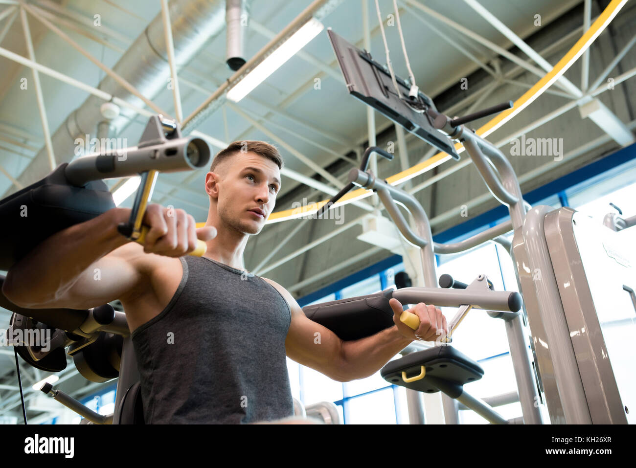 Low angle portrait of handsome young man pumping arm muscles using ...