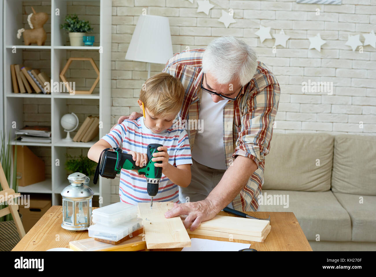 Portrait of senior man helping little boy make wooden model, teaching ...