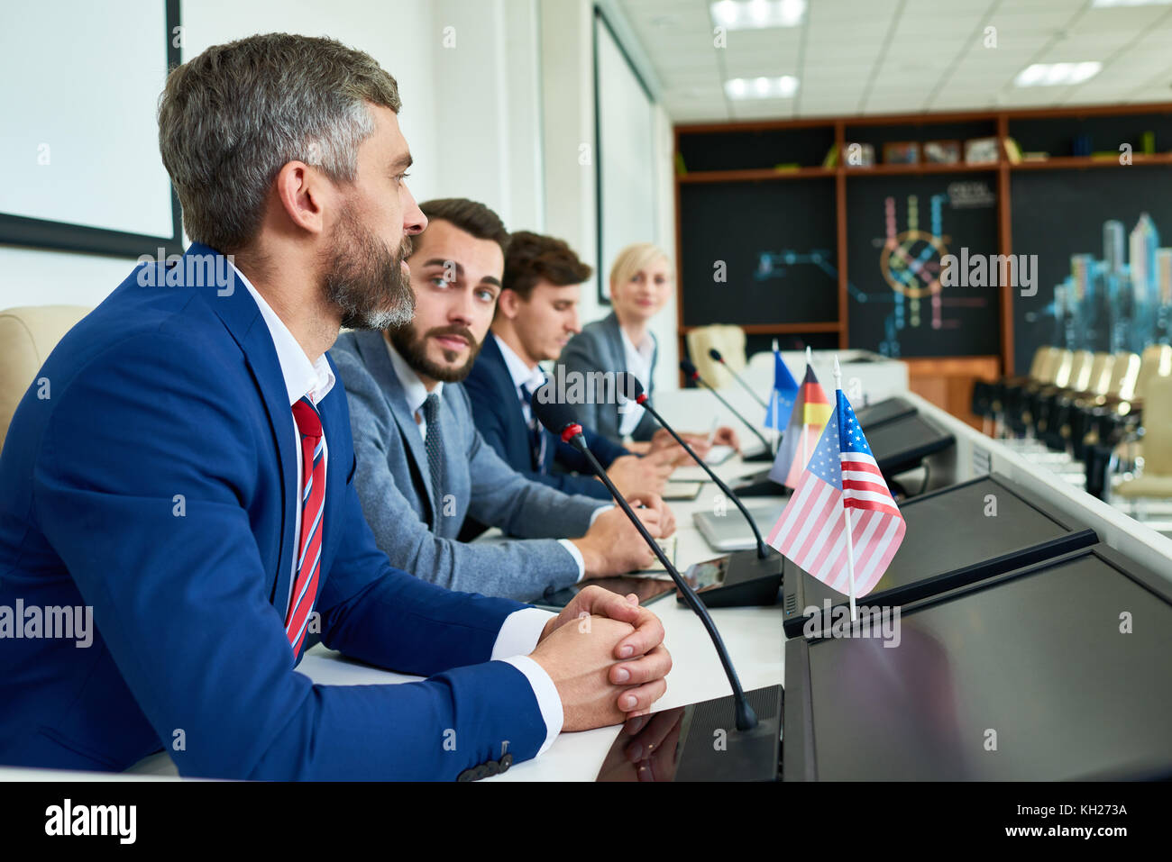 Portrait of several business people sitting in row participating in ...