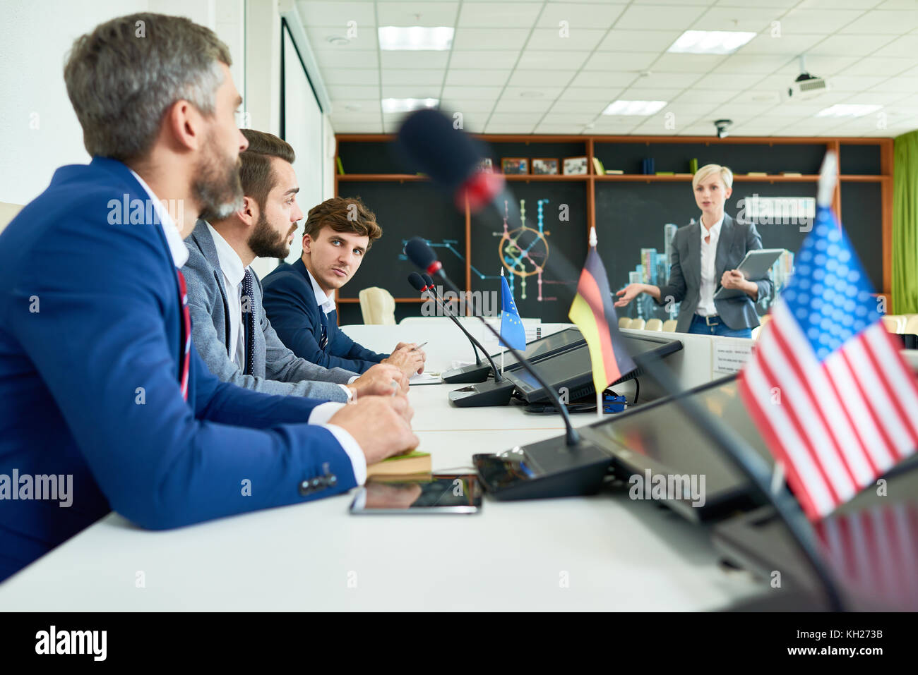 Side view of several business people sitting in row participating in ...