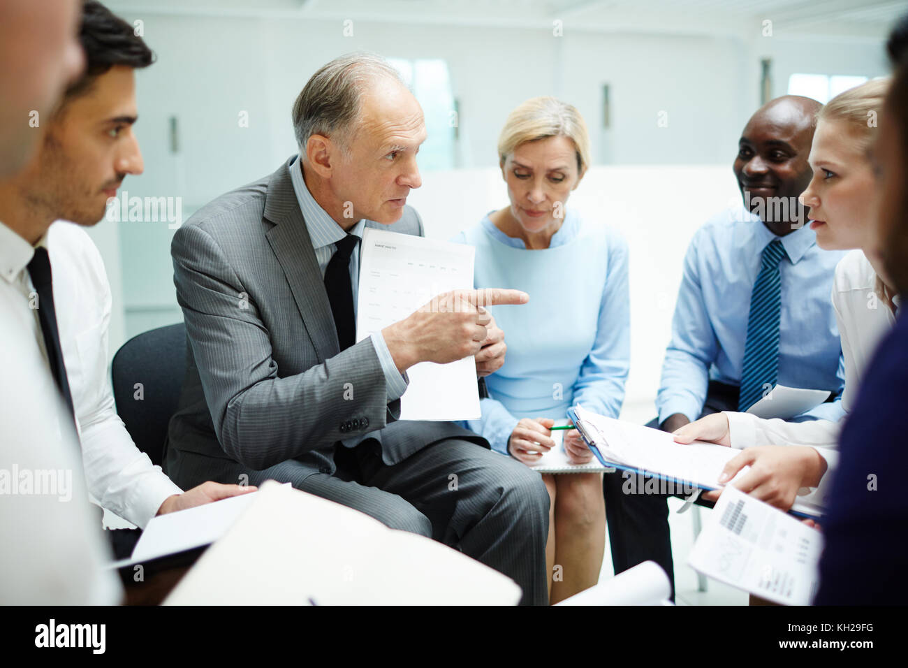 Confident mature director with financial paper pointing at one of ...