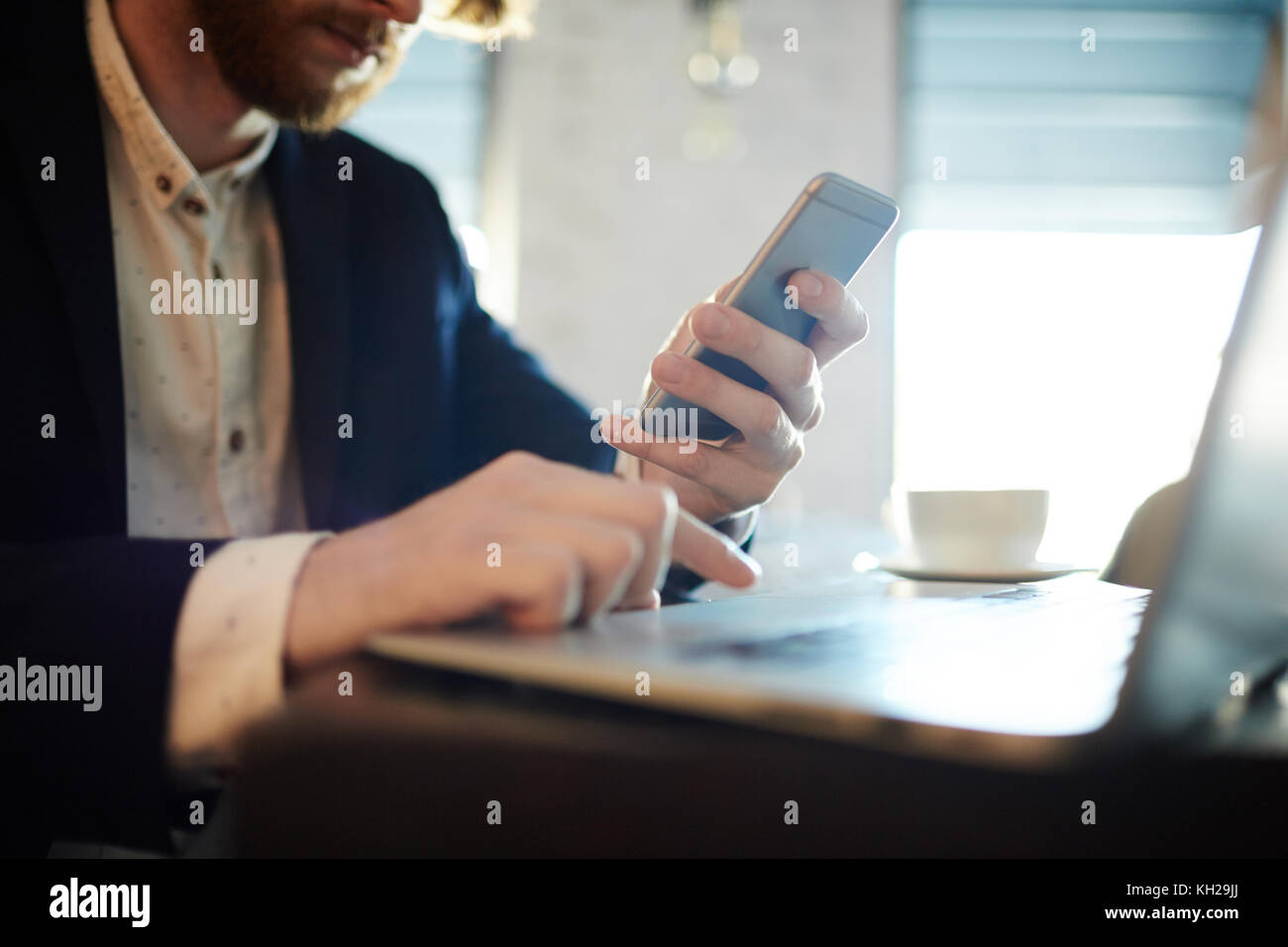 Young man with smartphone and laptop messaging at work Stock Photo - Alamy