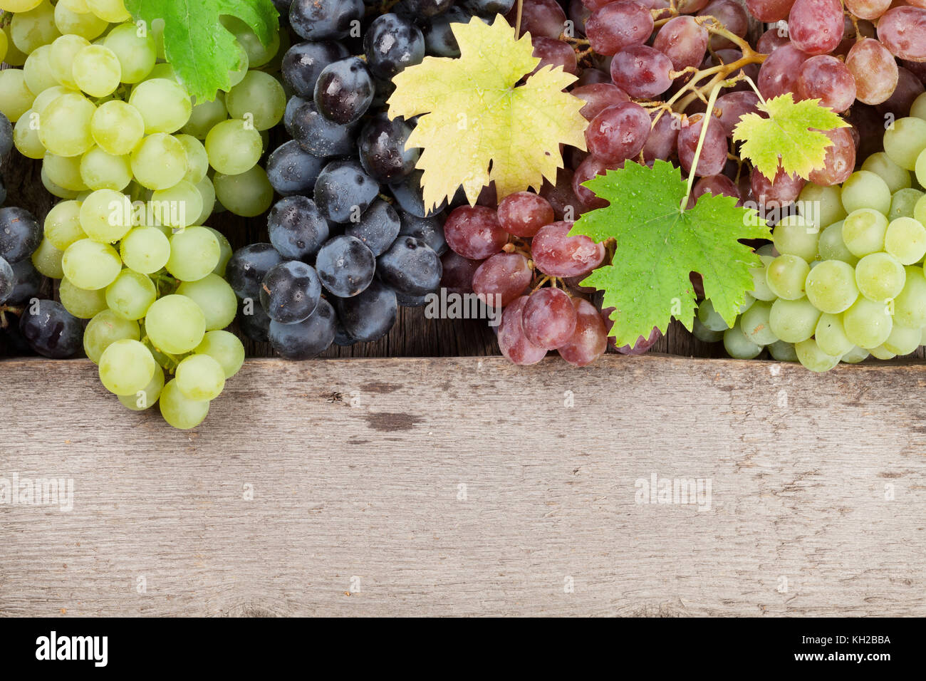 Various colorful grapes on wooden background. With space for your text ...