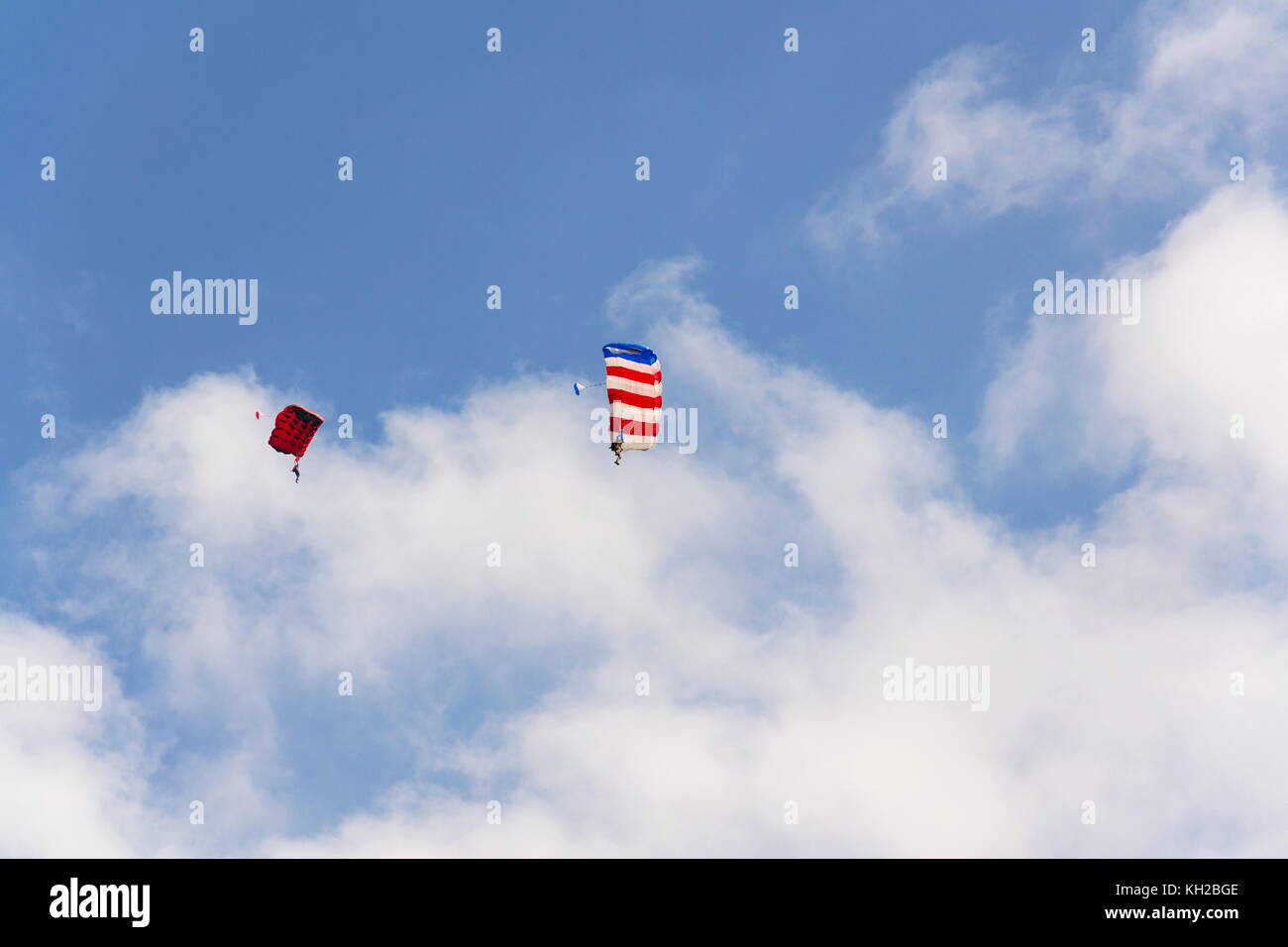 Two parachutists skydiving with colorful parachute clouds blue sky ...