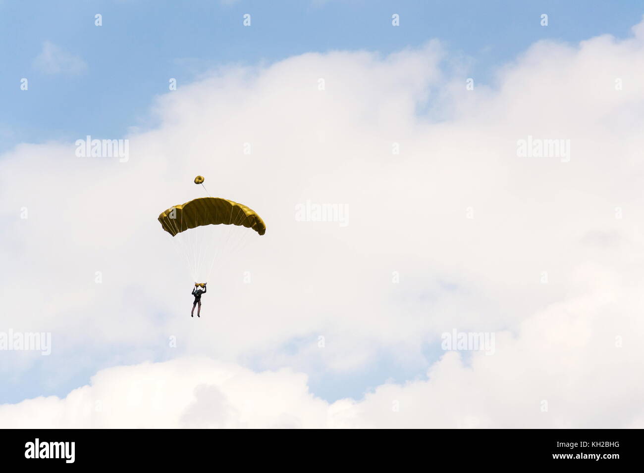 Parachutist skydiving with open yellow parachute clouds blue sky ...