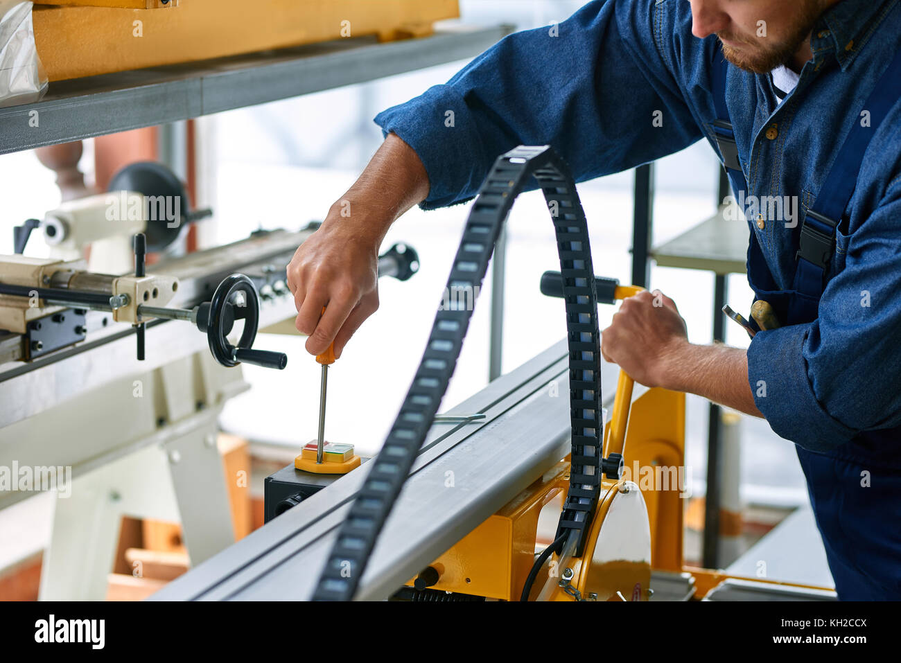 Closeup of workman fixing machine unit tying screws with screwdriver at ...