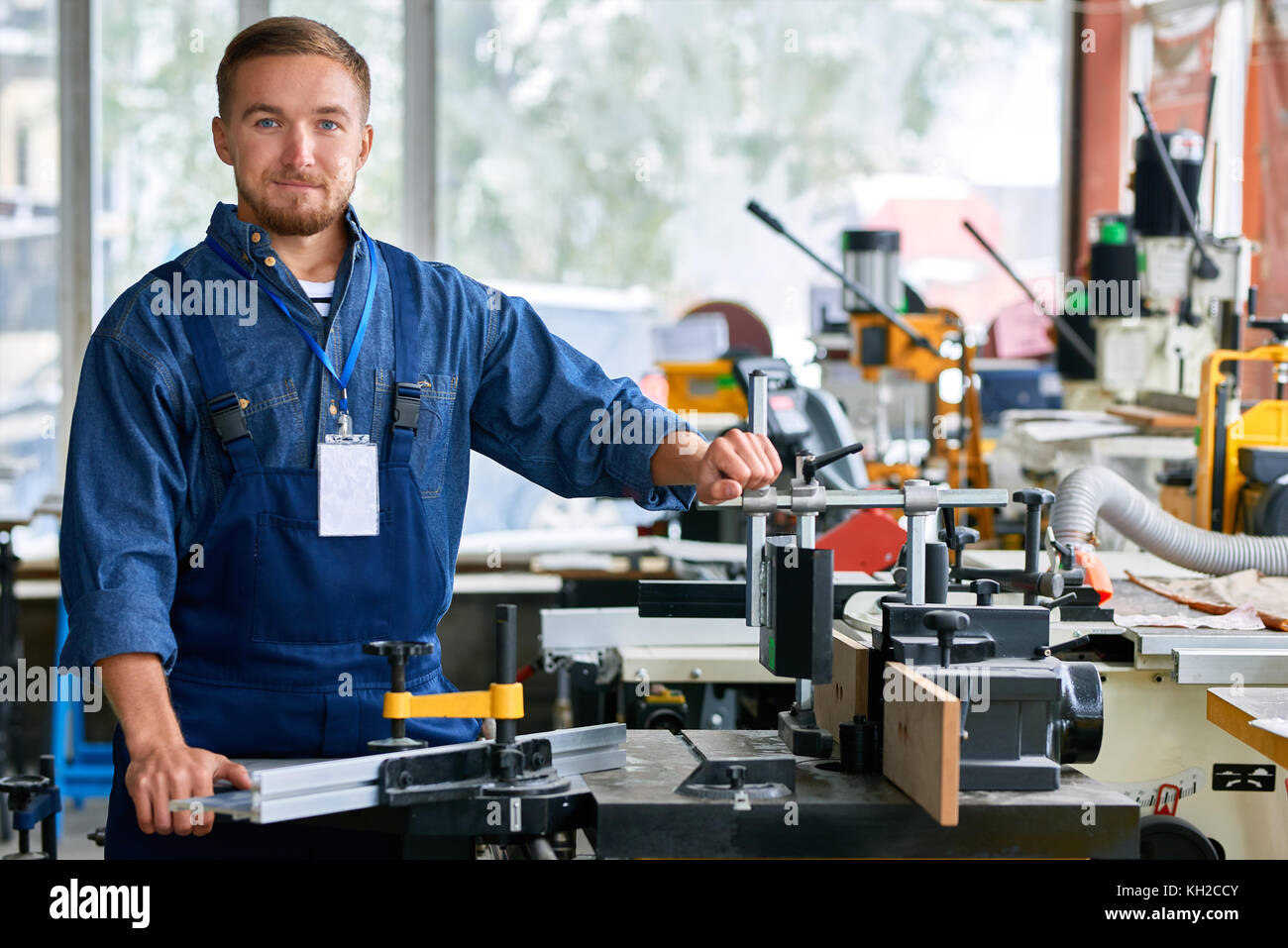 Portrait of young worker posing looking at camera with machine units in ...