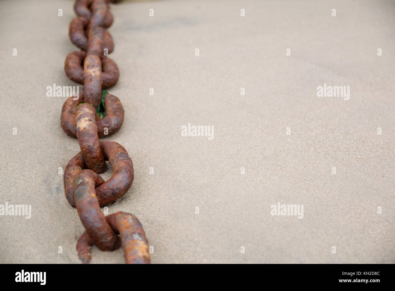 Rusty old boat chain on a sandy beach with a shallow depth of field ...