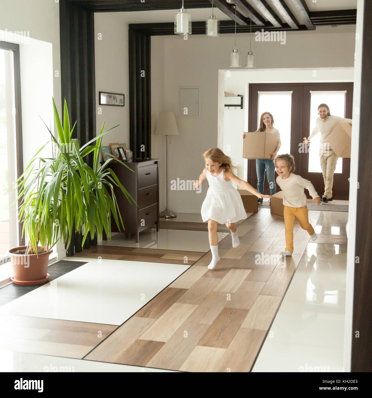 Playful happy kids running into new big own beautiful house, family ...