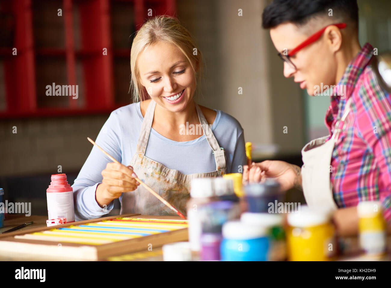 Portrait of two modern female artists enjoying working together in art ...