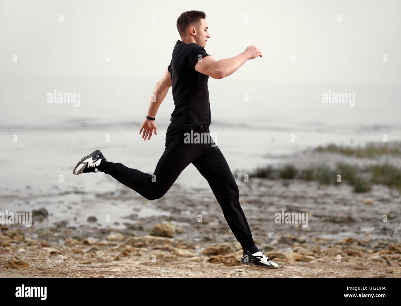 Athletic man running by the rocky seaside coast Stock Photo - Alamy