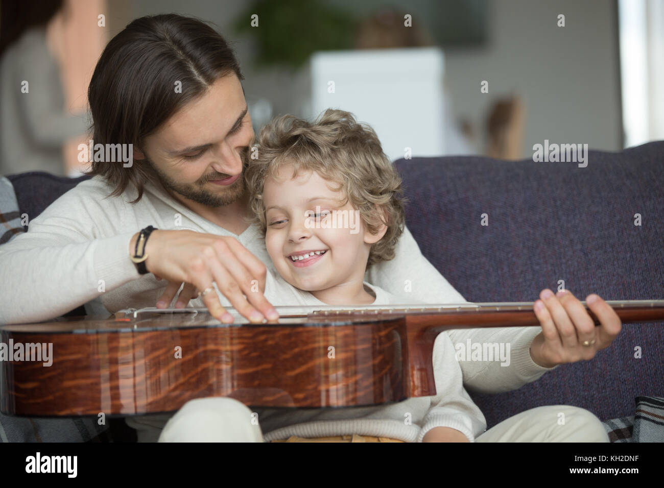 Young father teaching little son to play musical instrument at home ...