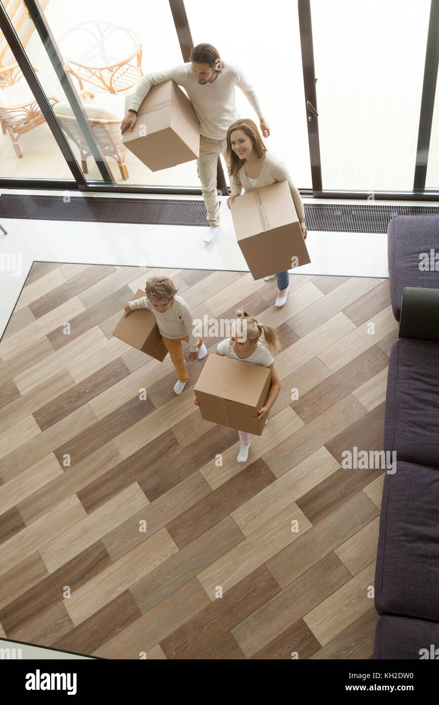 Young family with kids entering new home carrying boxes, children ...