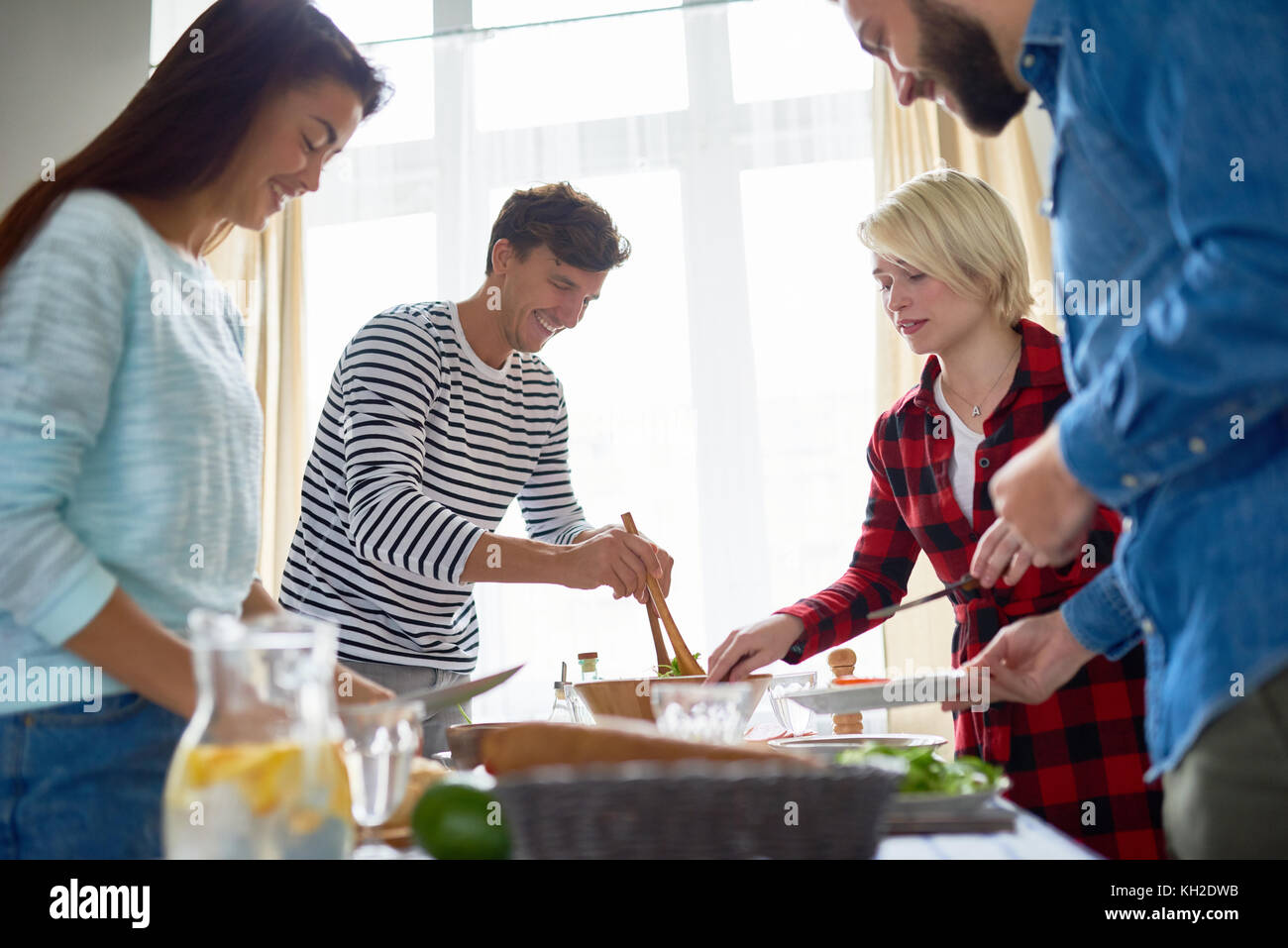Group of young people preparing dinner for festive celebration standing ...