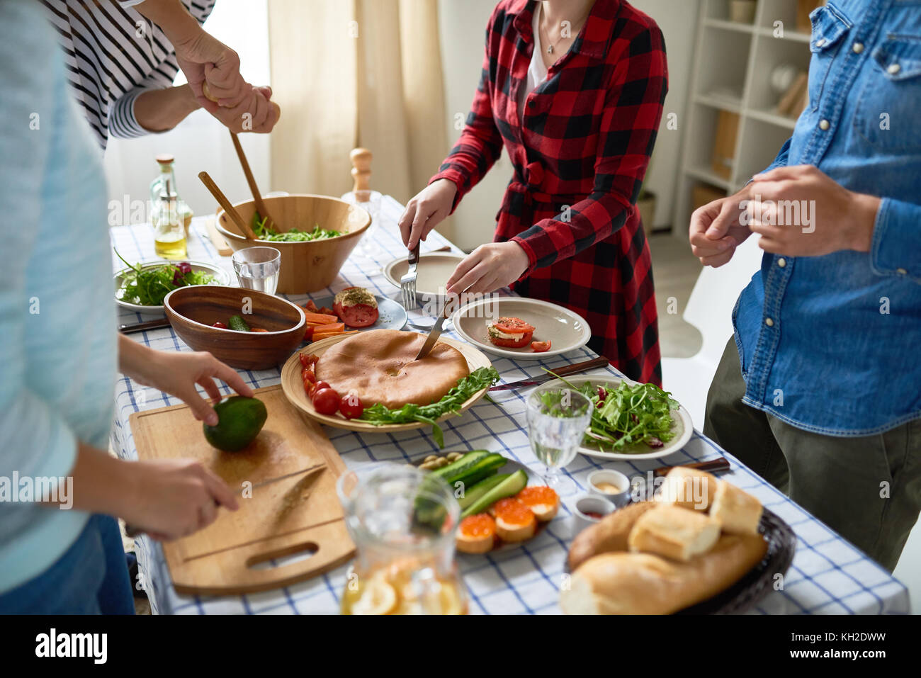 Low section of unrecognizable people cutting pie and vegetables ...