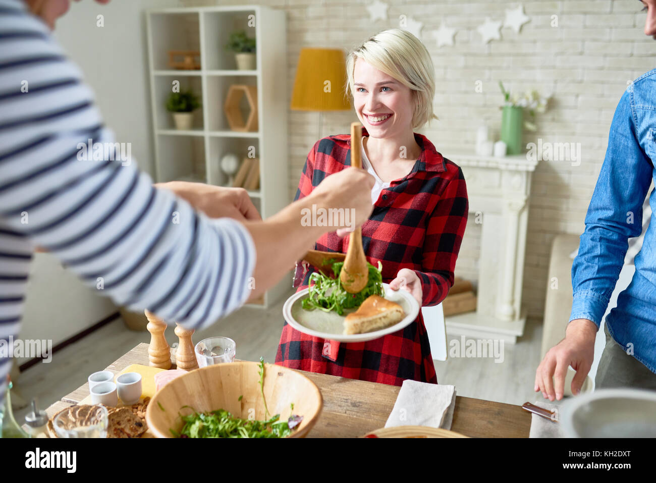 Group of modern young people standing at big table with food on it ...