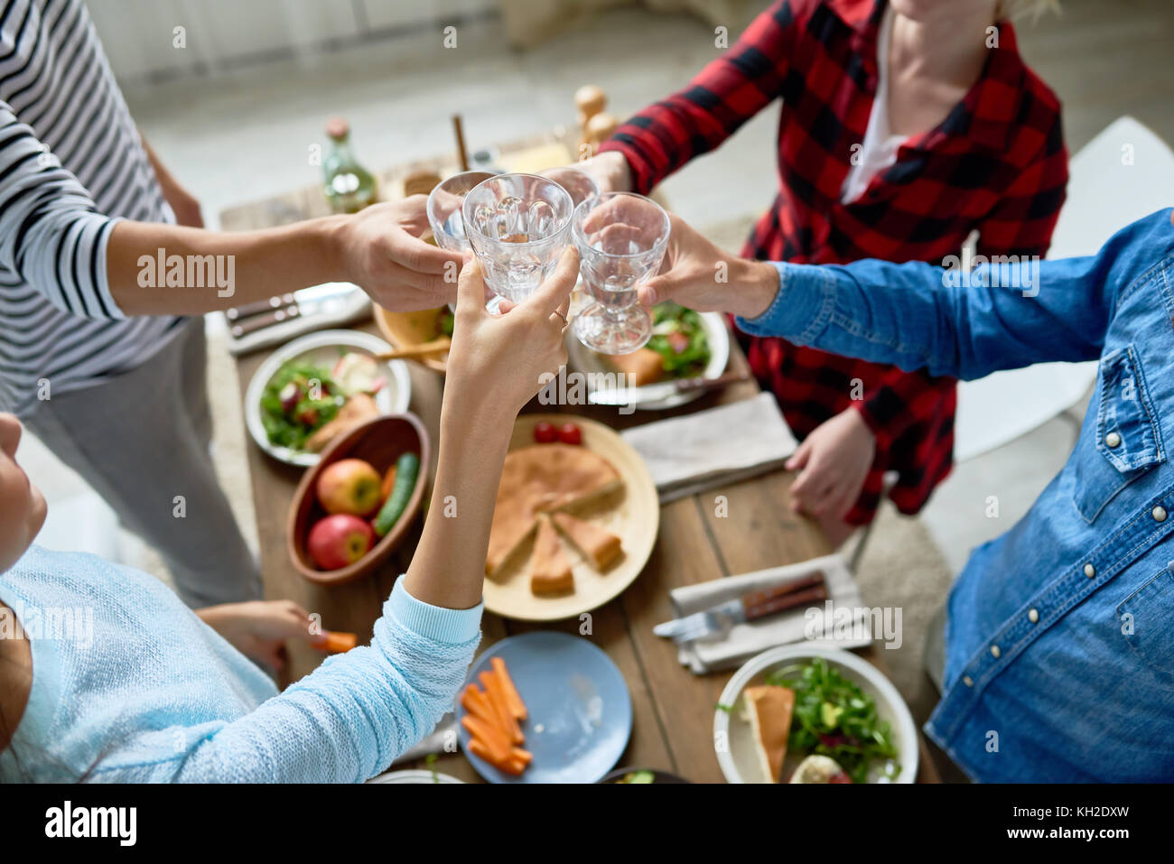 Group of friends enjoying dinner together standing at big table with ...