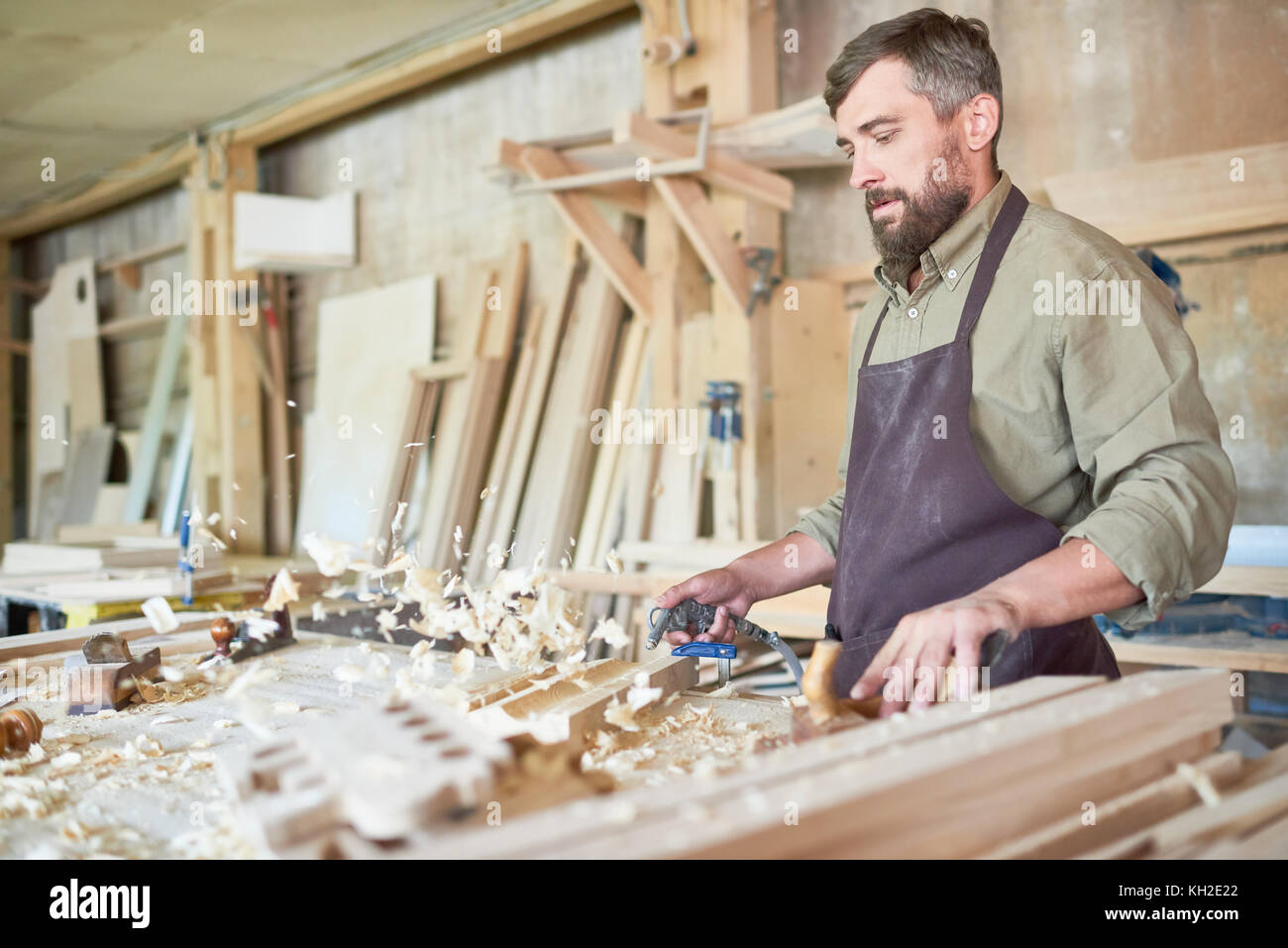 Portrait of mature bearded carpenter making furniture in modern ...