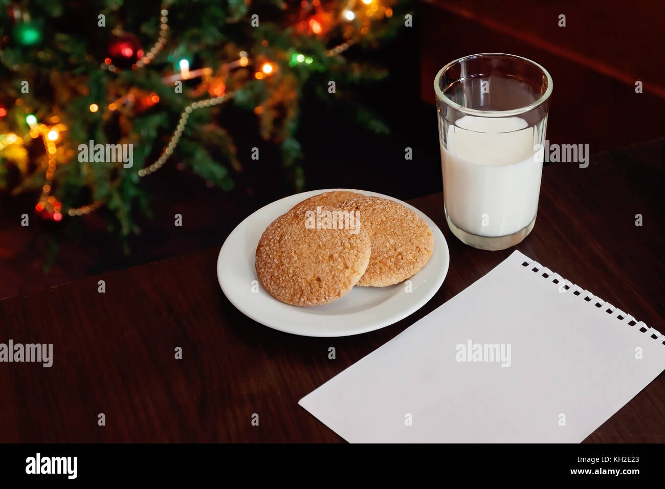 Christmas cookies and milk with note for Santa in front of lights of ...
