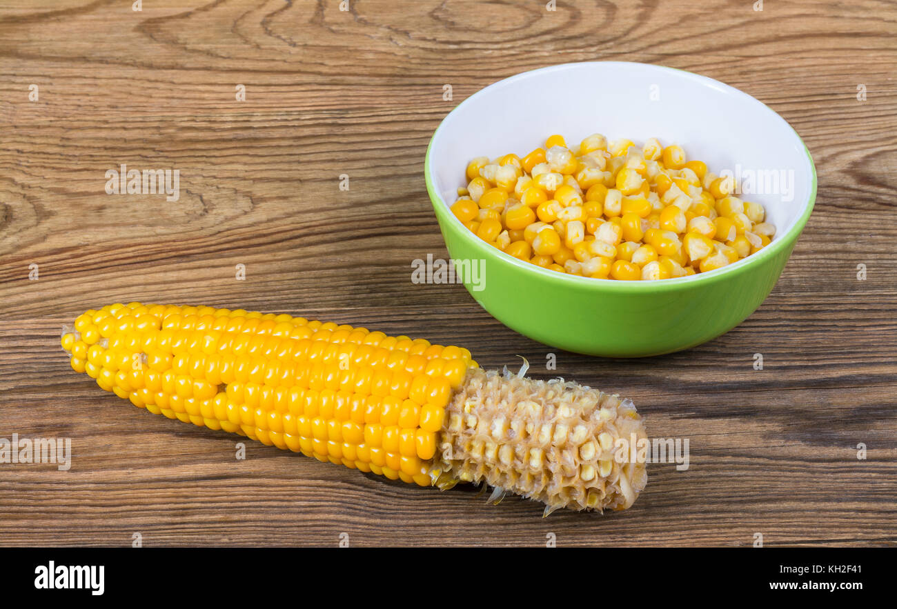 Partially empty corncob and heap of boiled maize. Yellow corn grains in ...