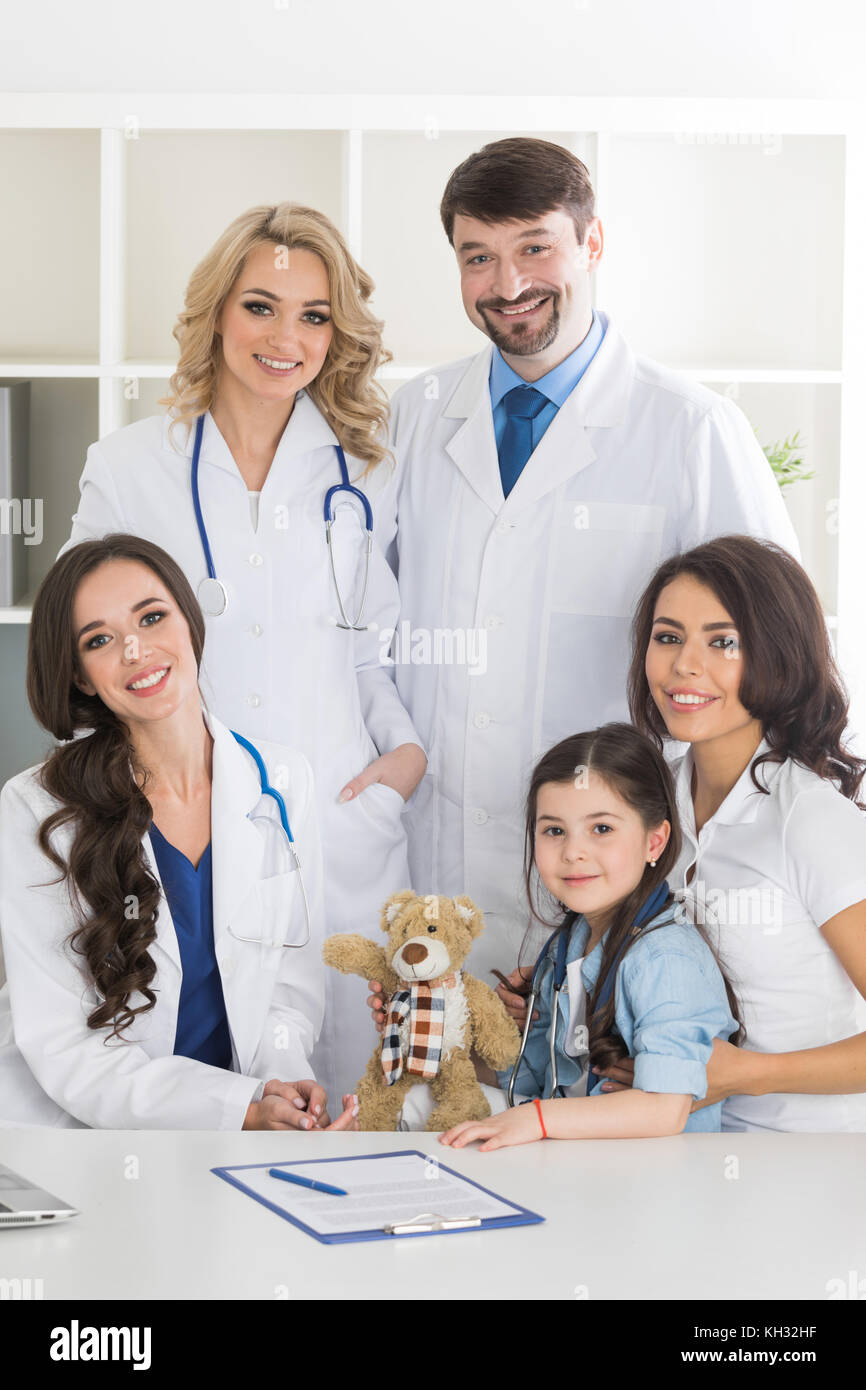 Young Mother With Daughter And Droup Of Doctors In Clinical Office