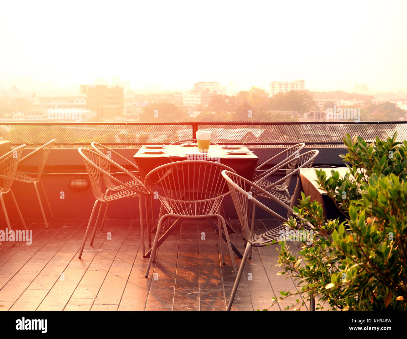 Dinning table set at rooftop looking down city view at colorful sunset ...