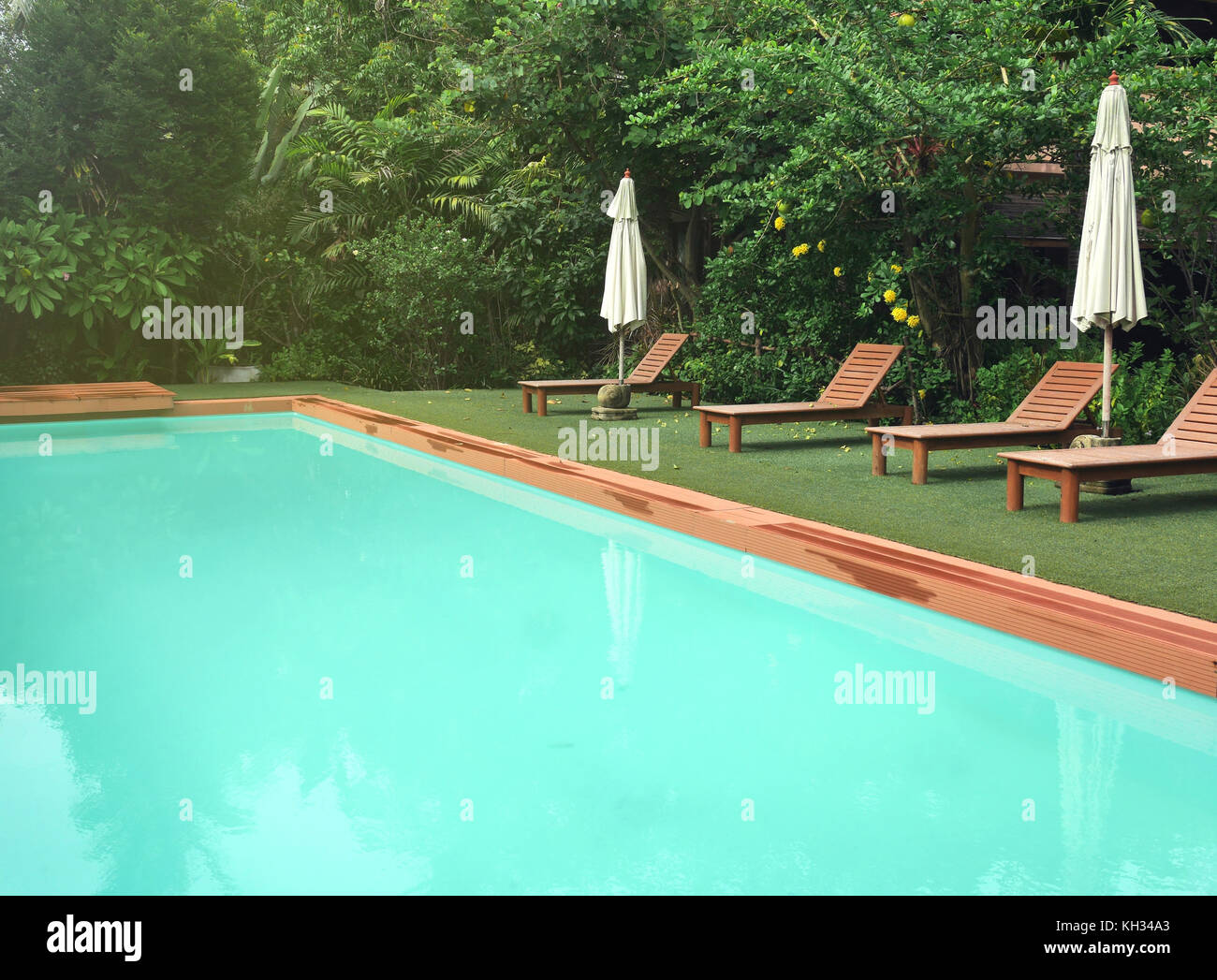 Tranquil blue pool in the morning with poolside chairs and unopened ...