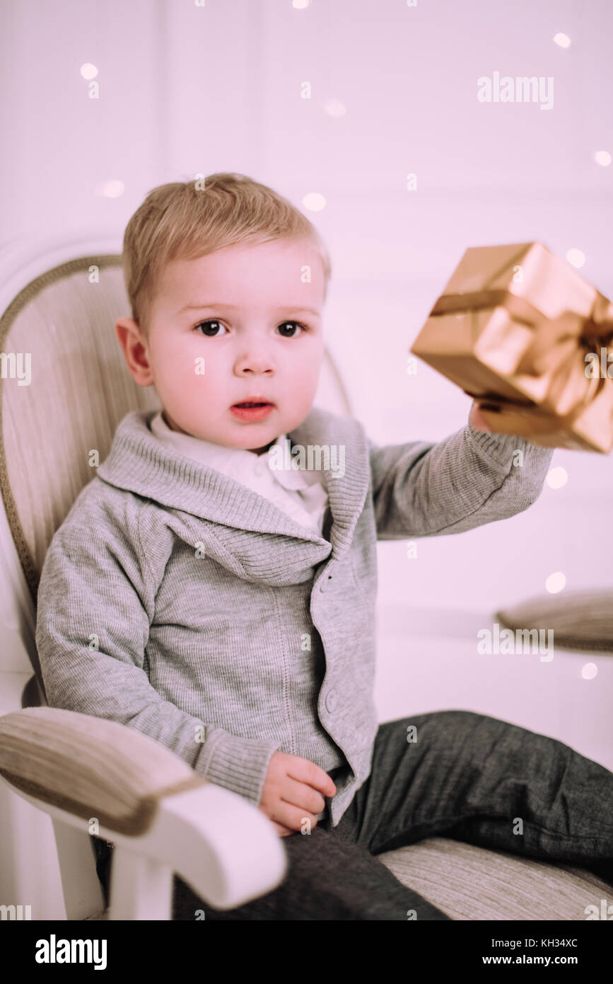 Cheerful little baby boy playing near Christmas tree, gold and beige ...