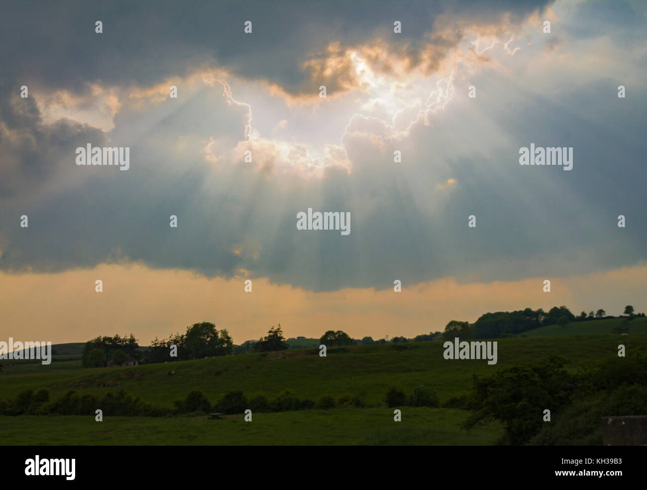 Shafts of sunlight shine through heavenly clouds illuminating earth ...