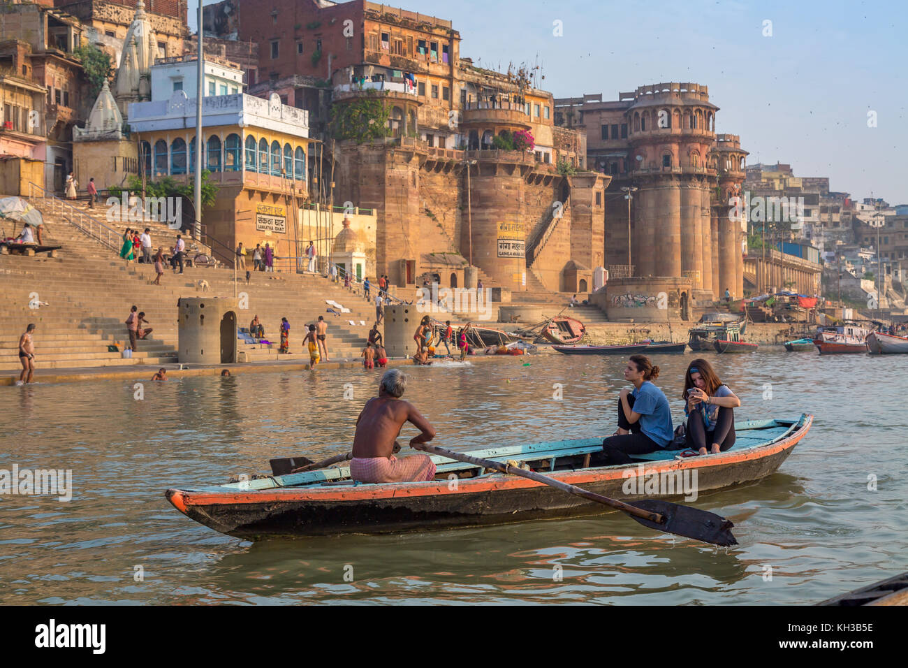 Tourists enjoy boat ride along the Ganges river ghat with view of ...