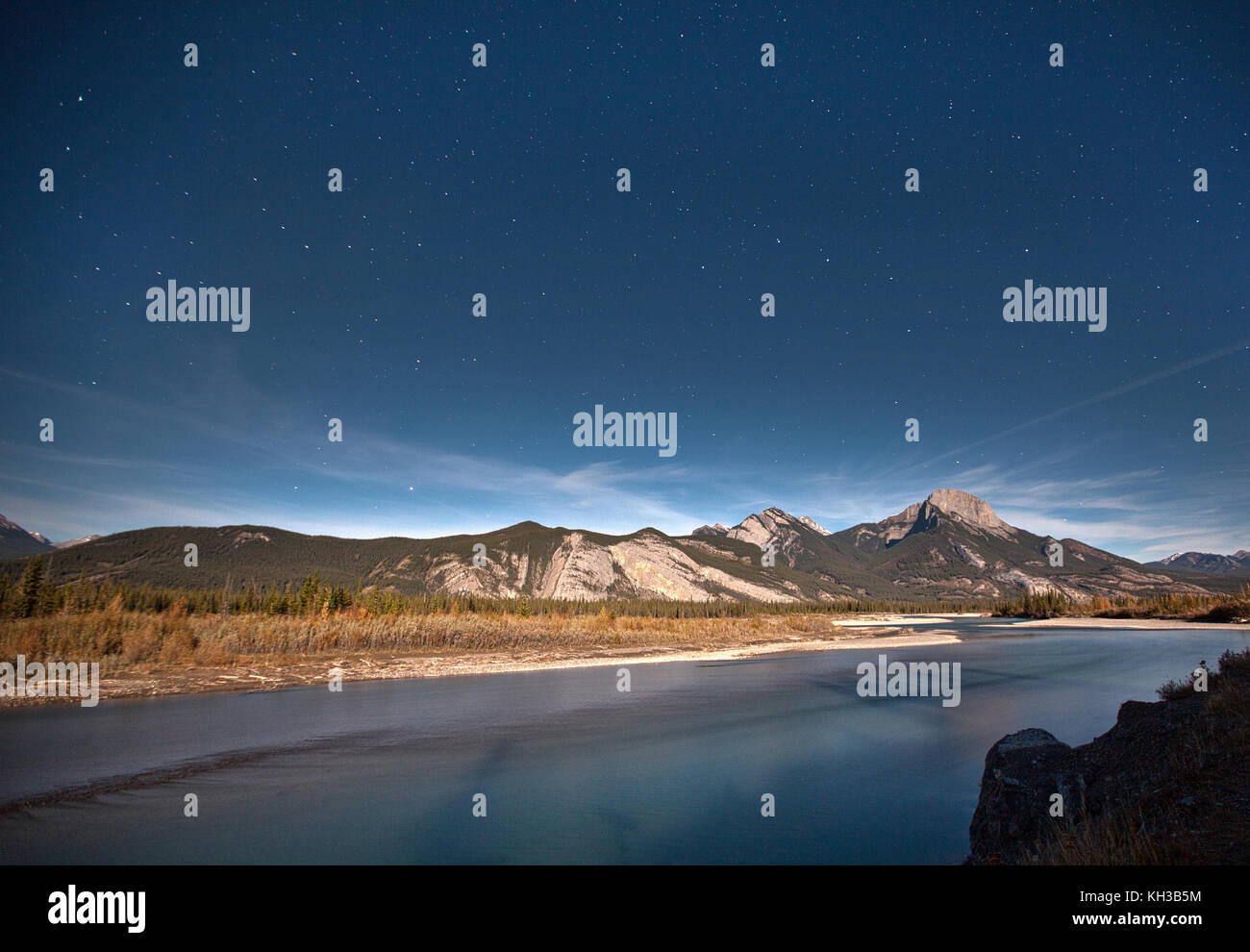 a night sky filled with stars above a mountain in the Canadian Rockies ...