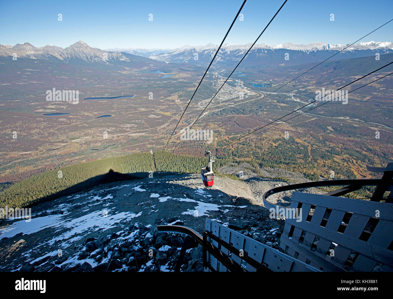 view from a mountain top down to the valley below with a red skytram ...