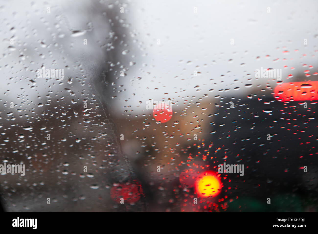 blurred rain and traffic form inside car or house window. drops in the ...