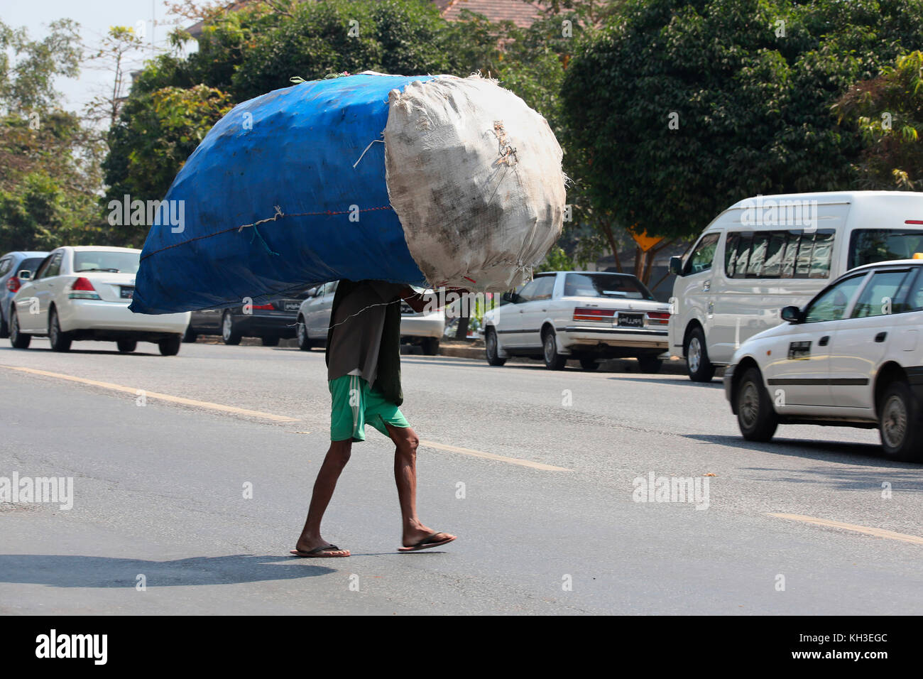 Local man carrying a heavy load of plastic bottles for recycling ...
