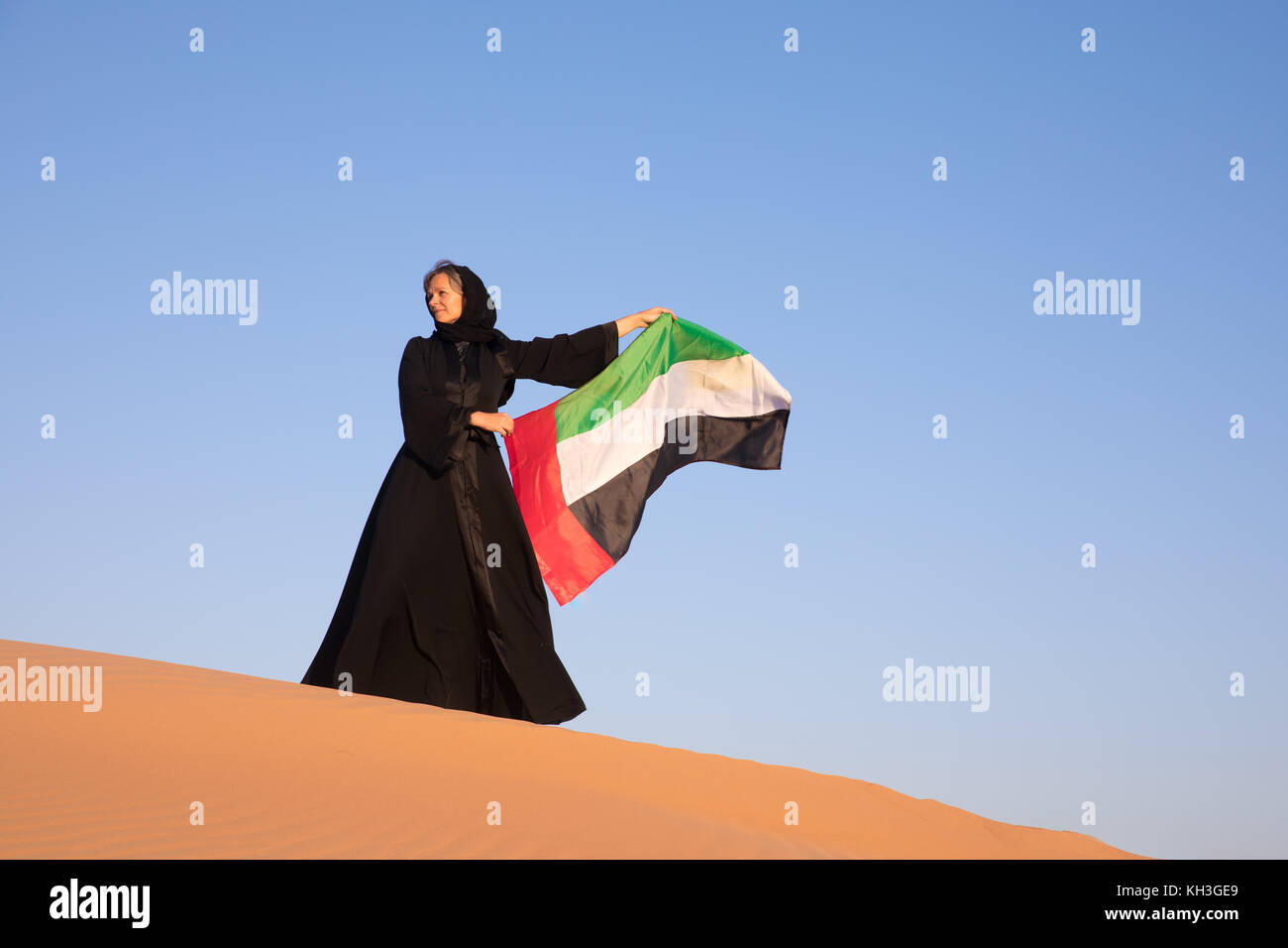 Beautiful woman in the national UAE dress abaya holding the United Arab ...