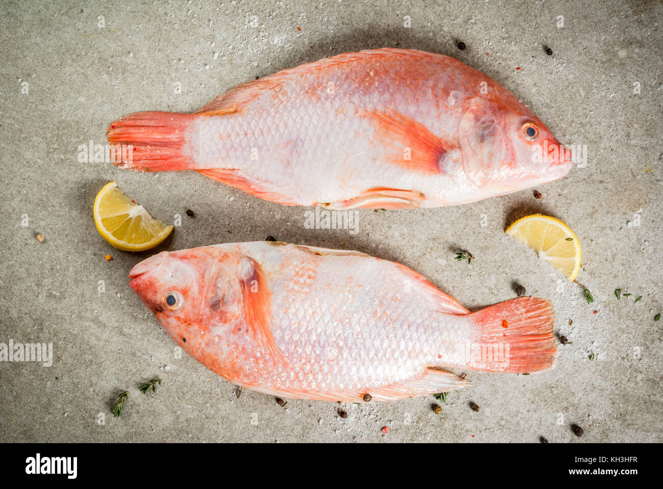 Fresh raw fish pink tilapia with spices for cooking - lemon, salt ...