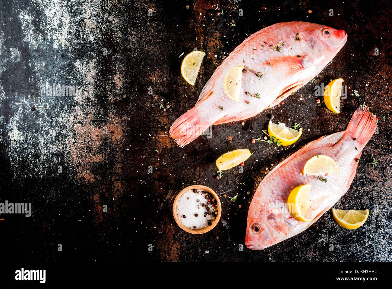 Fresh raw fish pink tilapia with spices for cooking - lemon, salt ...