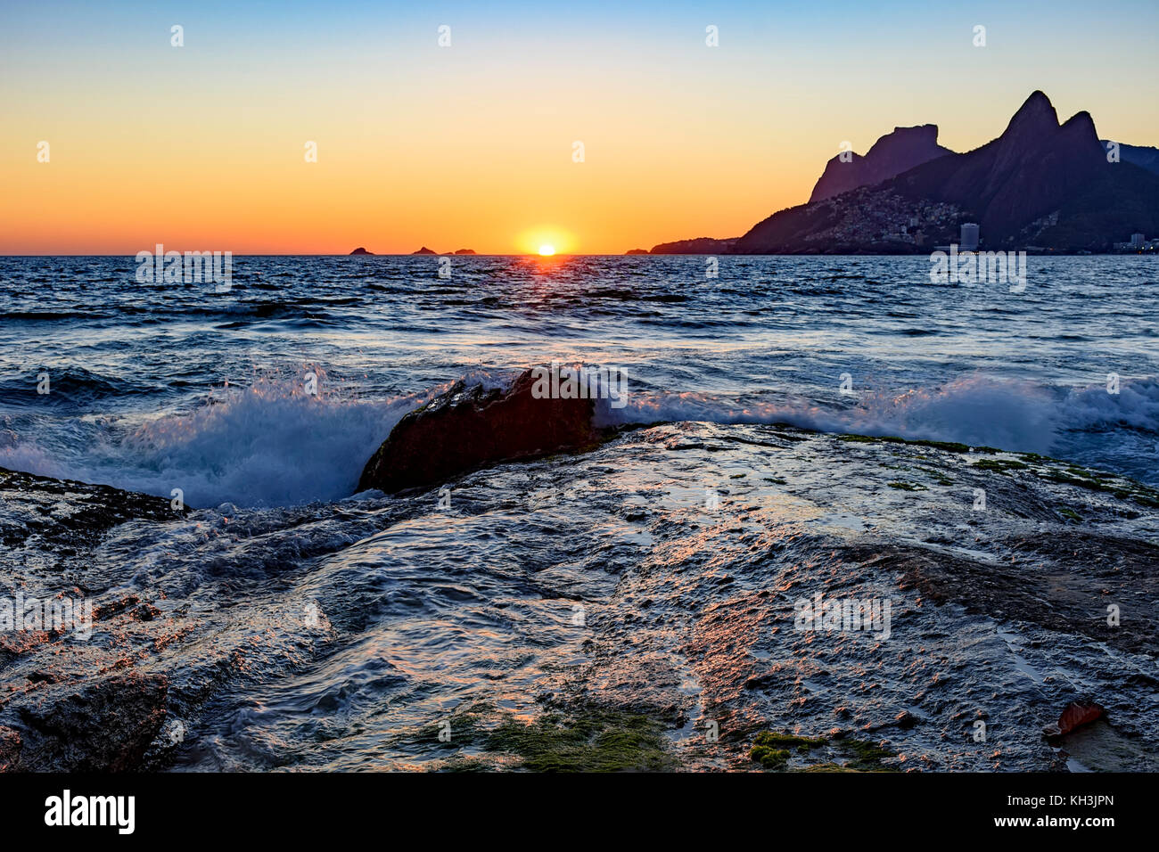 Sunset at the Arpoador stone, Ipanema beach with buildings and hills in ...