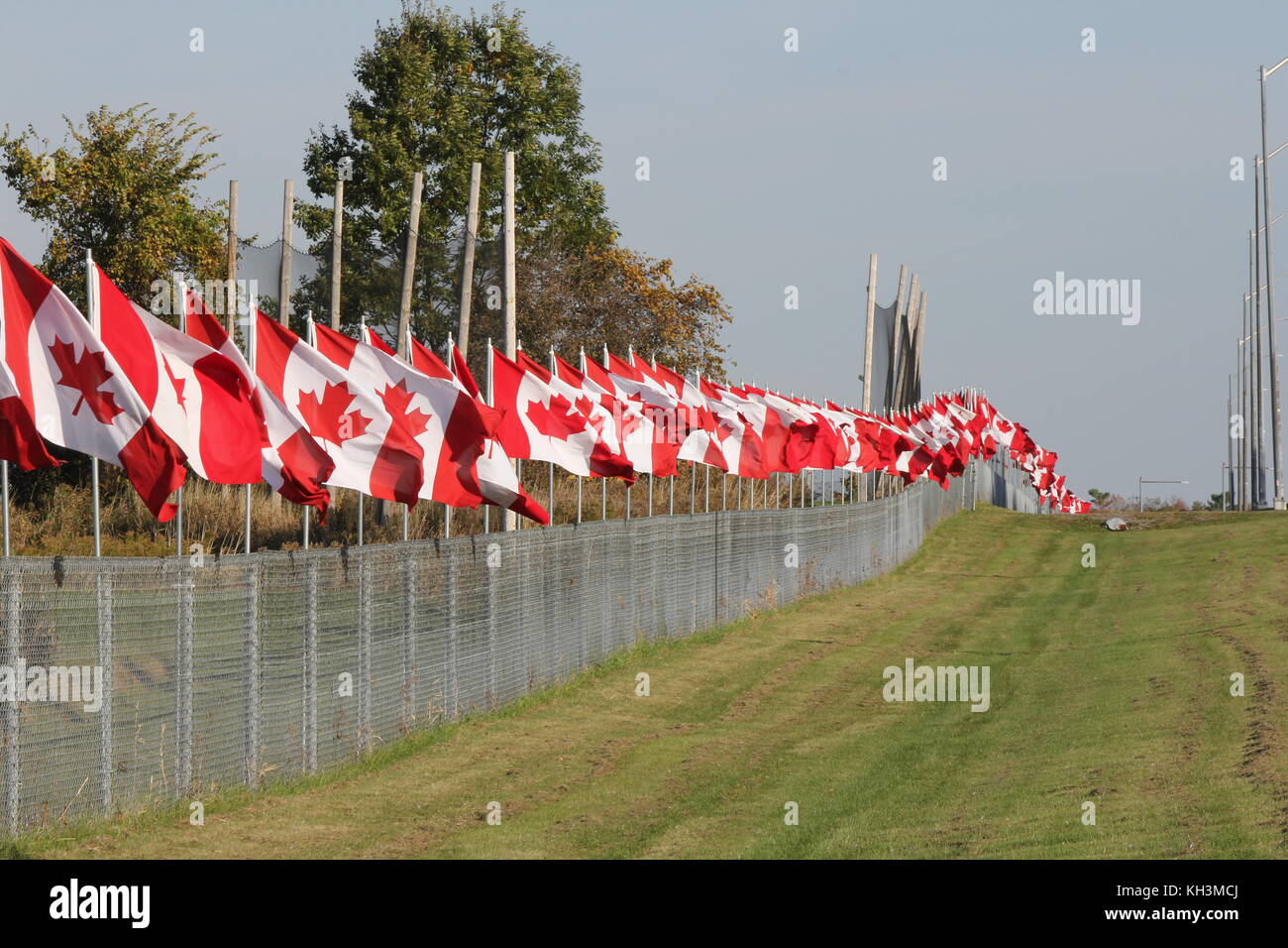 Row of Canadian flags, attached to fence rails in remembrance, gently ...