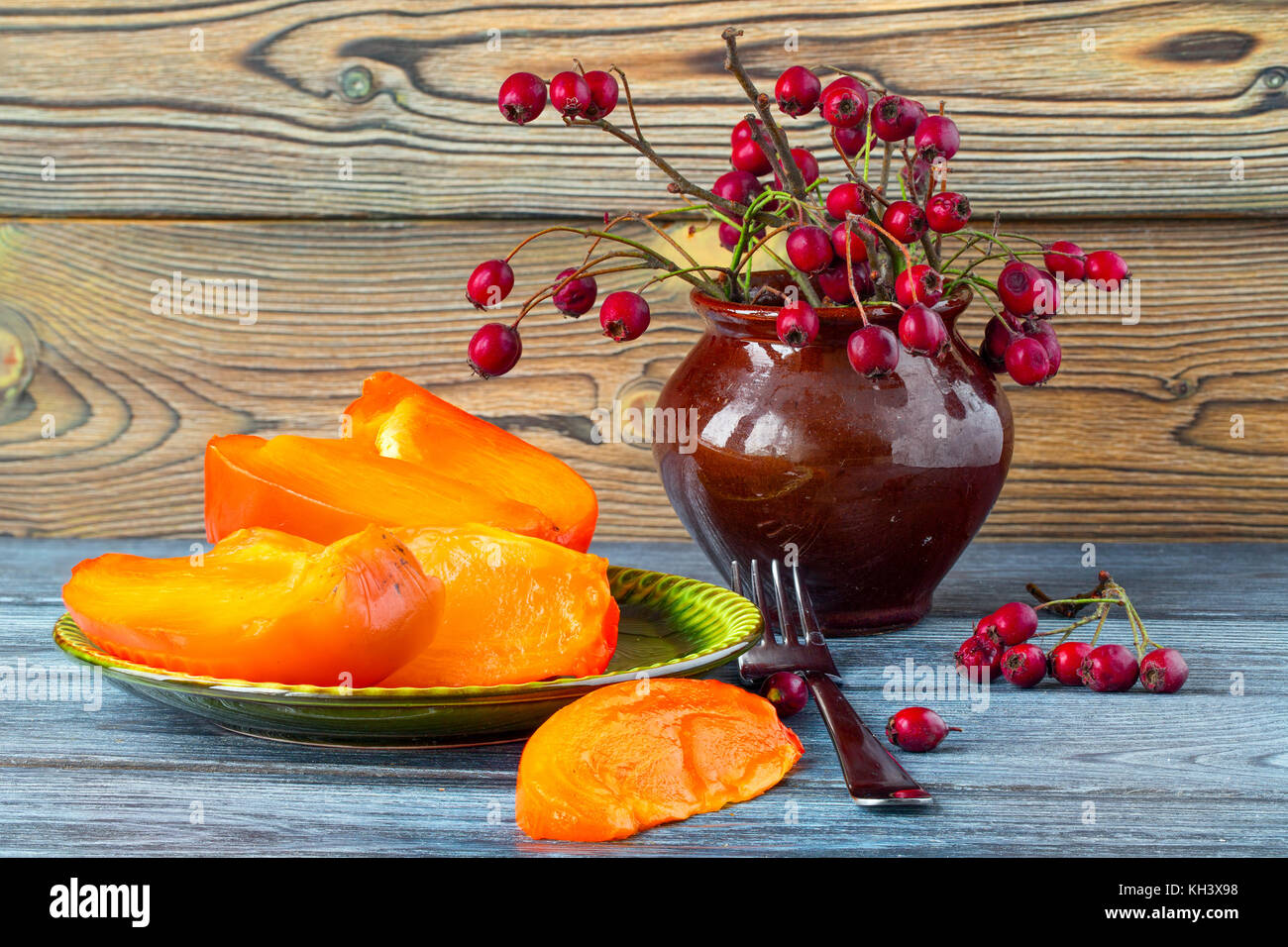 Segments of a ripe orange persimmon and berry of a hawthorn ...