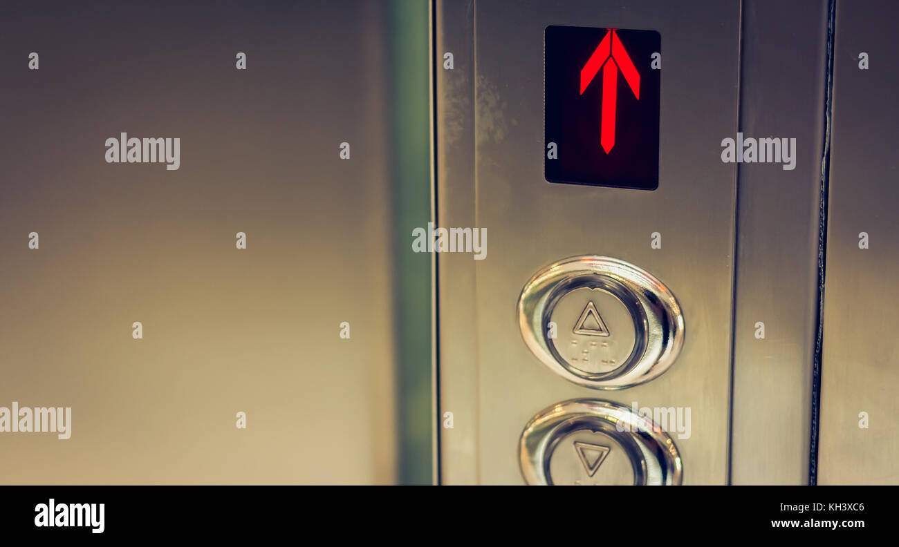 close up elevator button up and down and a screen that shows a red ...