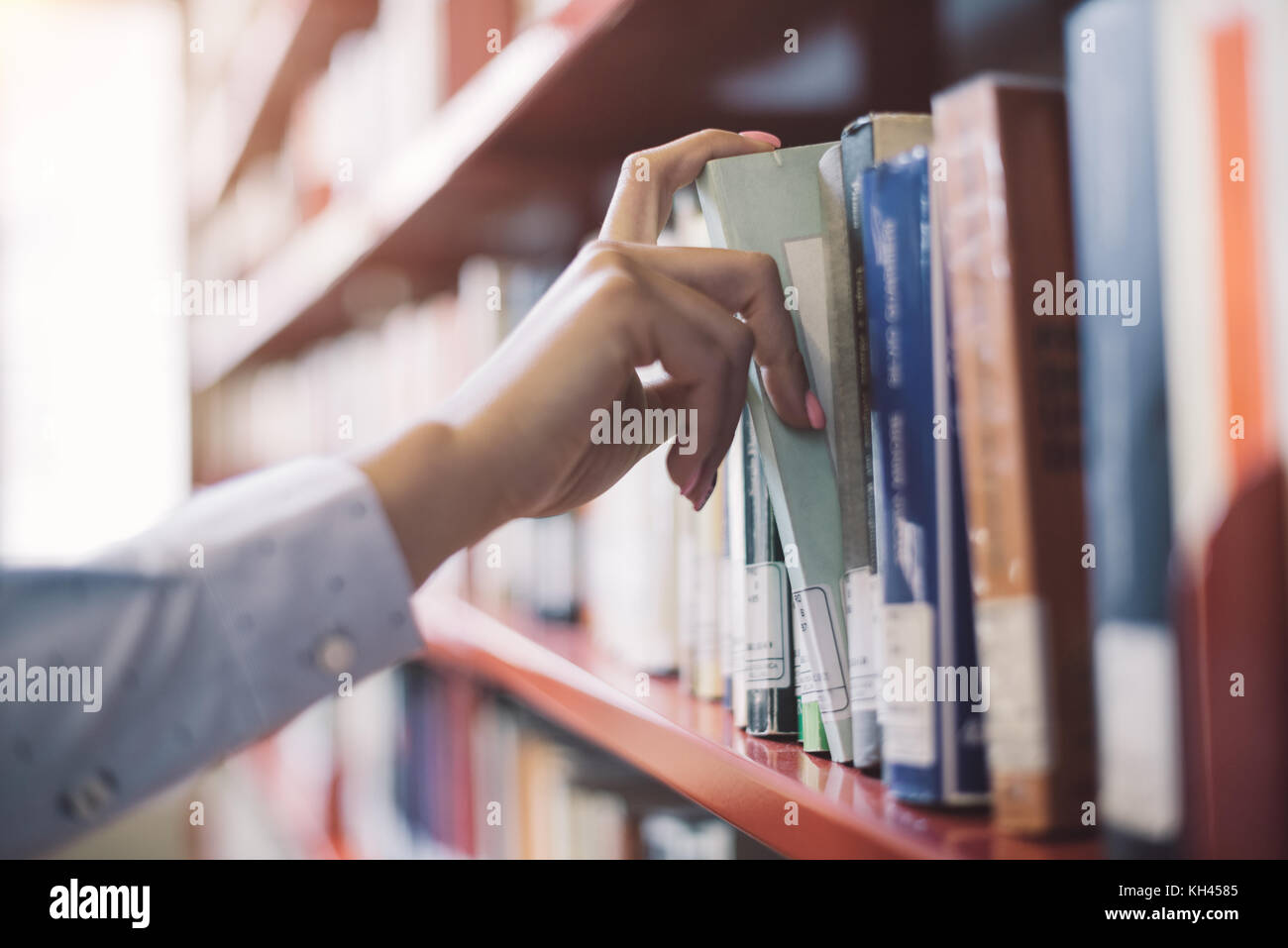 Woman at the library, she is searching books on the bookshelf and ...