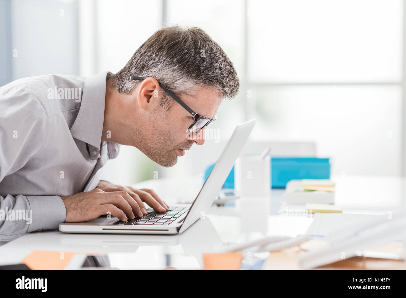 Businessman working at office desk, he is staring at the laptop screen ...