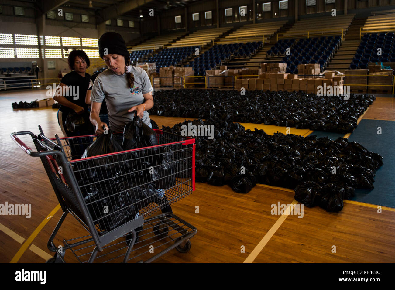 Volunteers help load food and water provided by FEMA at a distribution ...