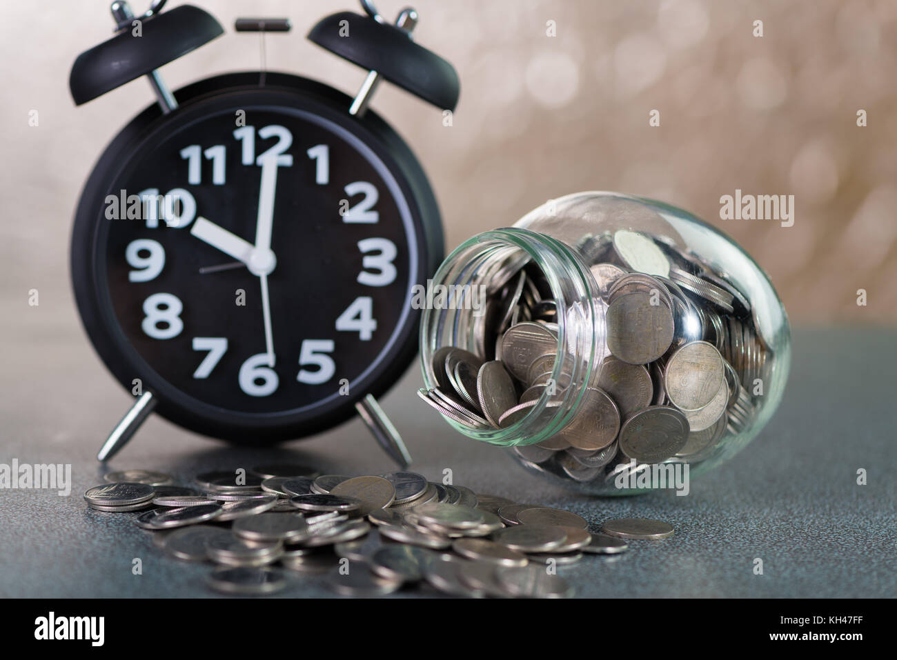 Alarm clock and step of coins stacks with coin in glass jar on working ...