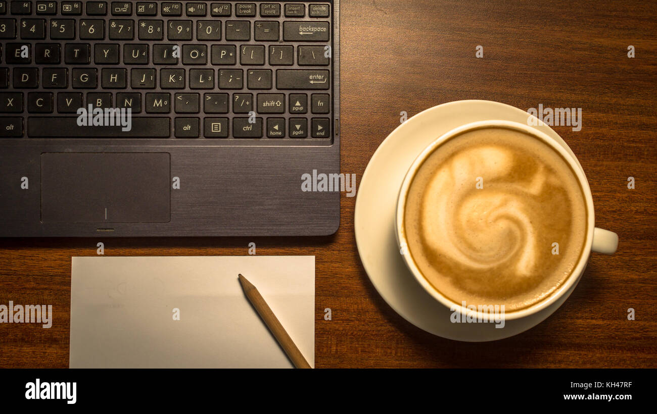 a cup of coffee, laptop, paper and pencil on the desk. working and ...