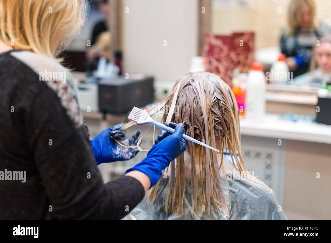 Hairdresser is dying female hair. Hands in glives with brush, coloring ...