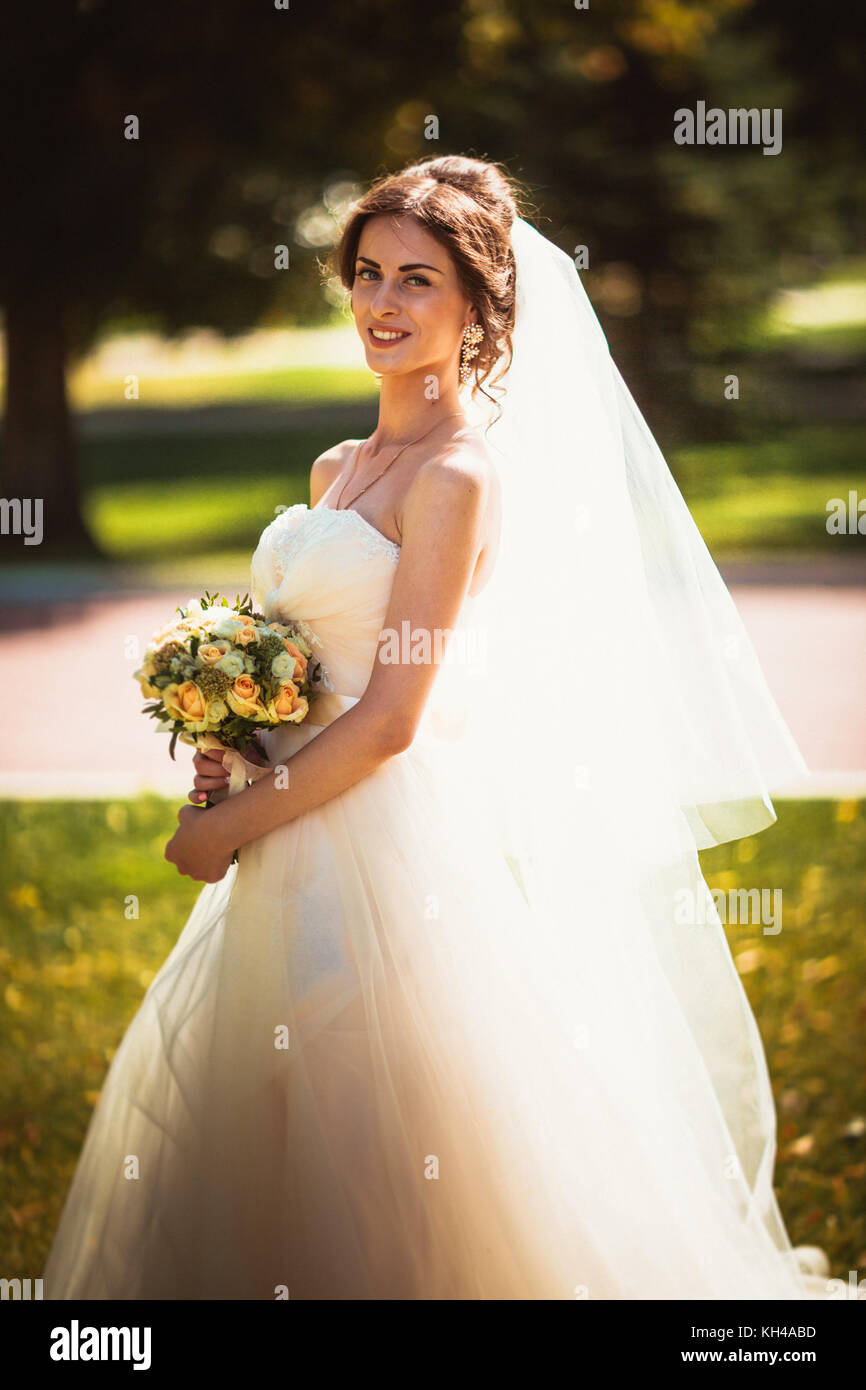 The beautiful brunette bride on a walk in park Stock Photo - Alamy