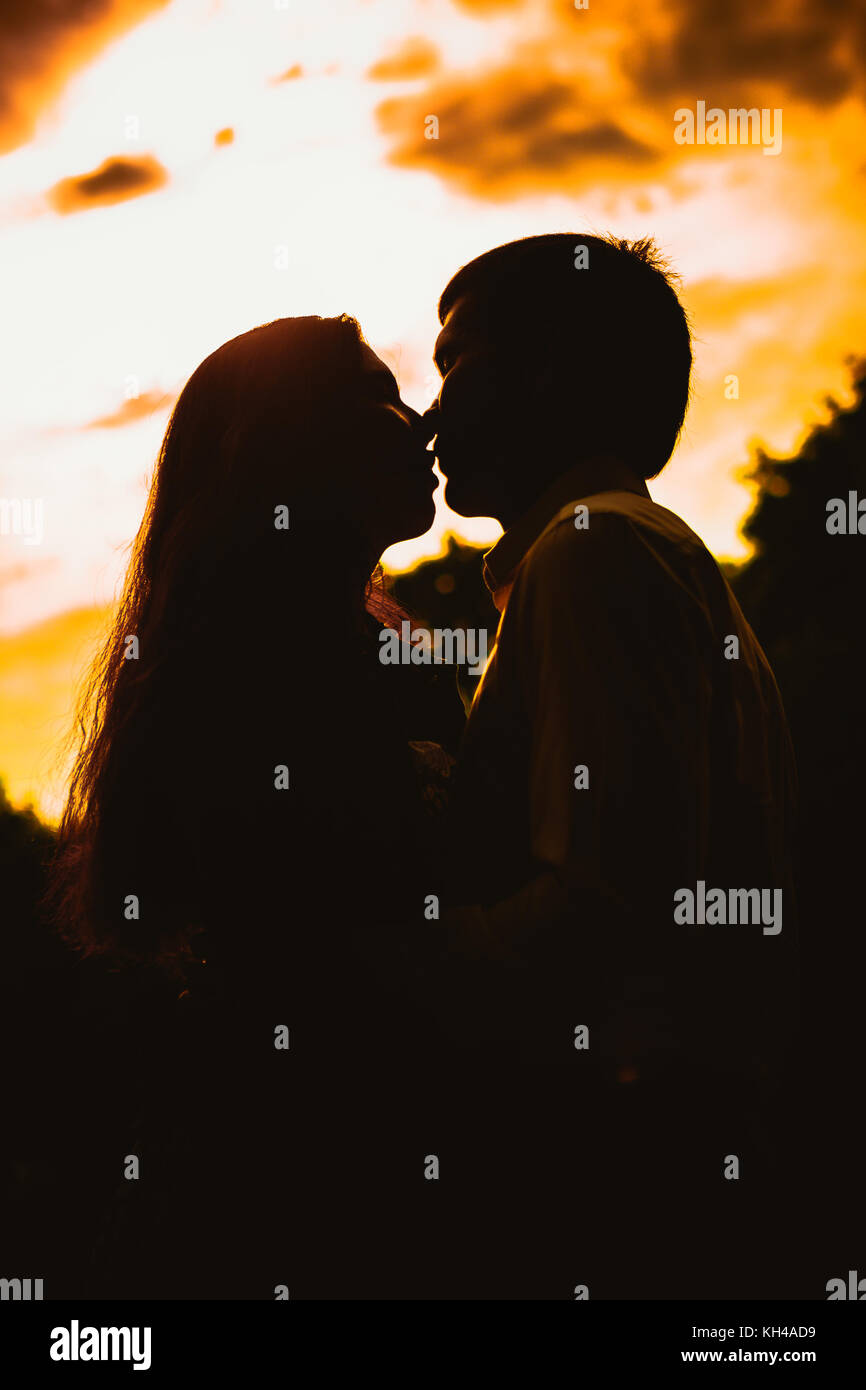Beautiful young couple on the sunset background Stock Photo - Alamy